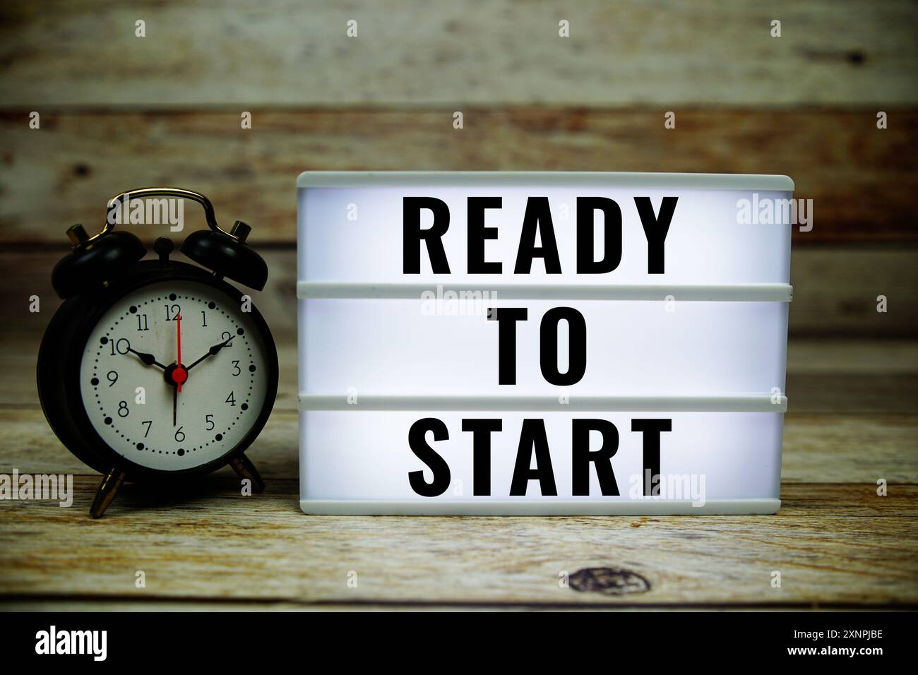 Ready to start text on LED lightbox with alarm clock on wooden ...