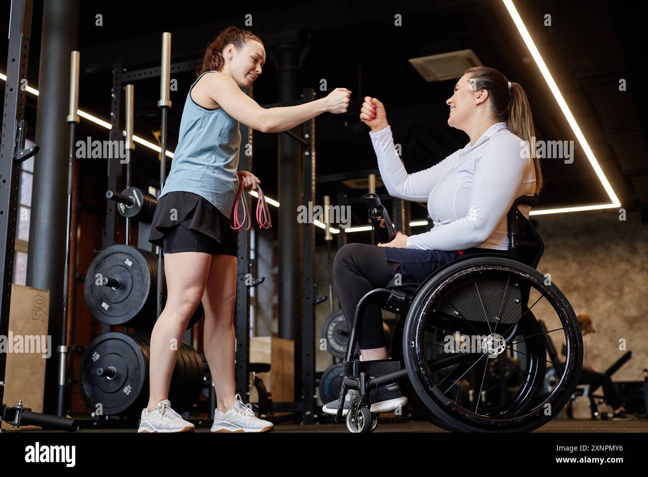 Full length side view of female fitness trainer fist bump with smiling ...