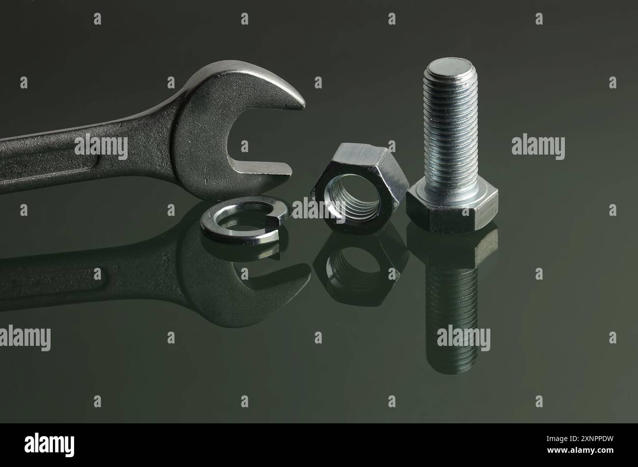 Wrench, bolt, nut and spring washer placed on a reflective surface ...