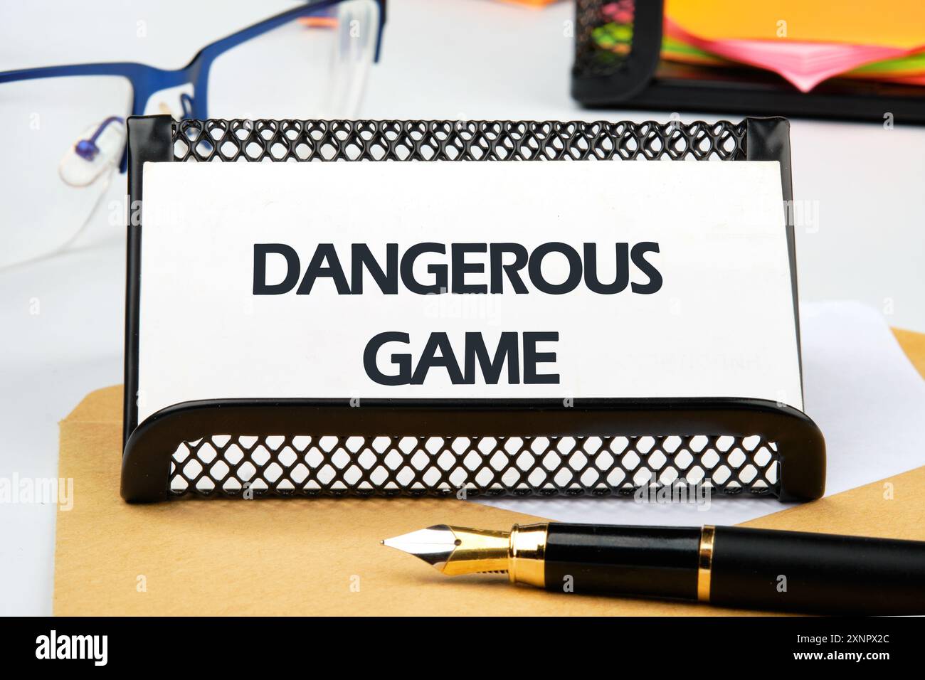 Text Dangerous game on a business card in a black stand Stock Photo - Alamy