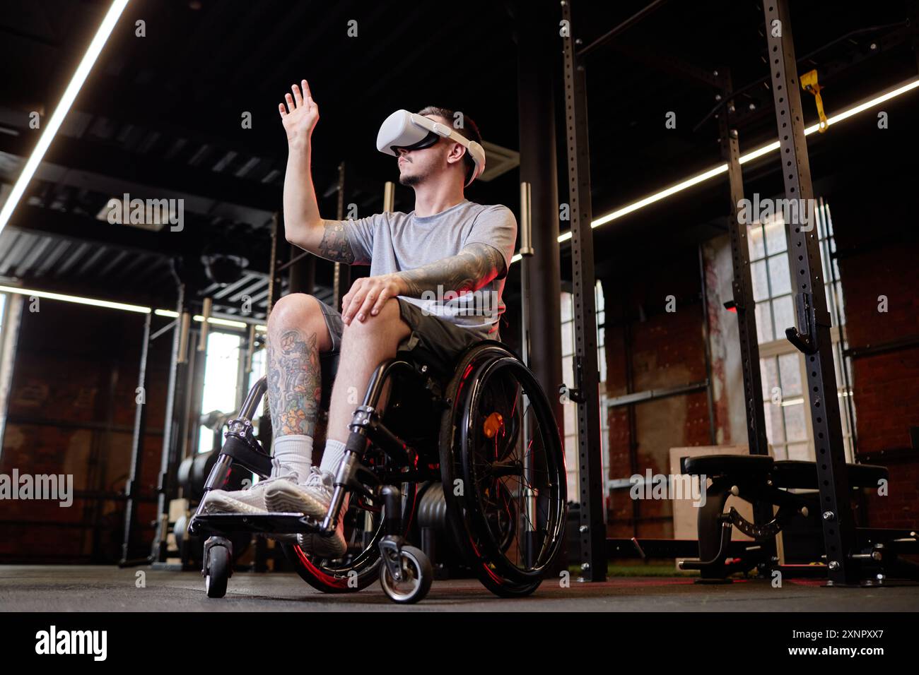 Side view portrait of young man with disability using wheelchair in gym ...