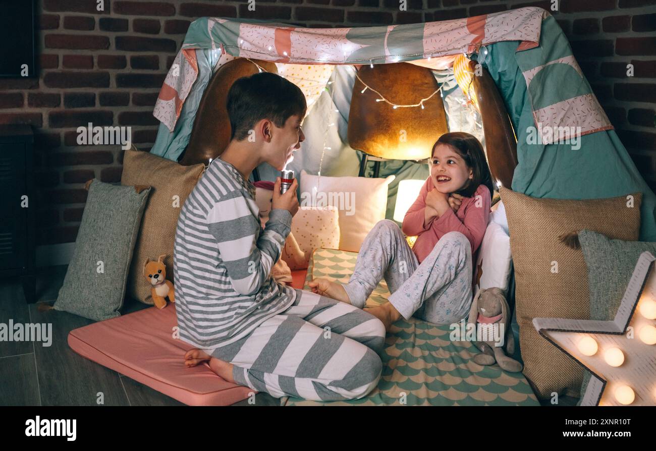 Happy little girl shrinking and shouting while brother making scary ...