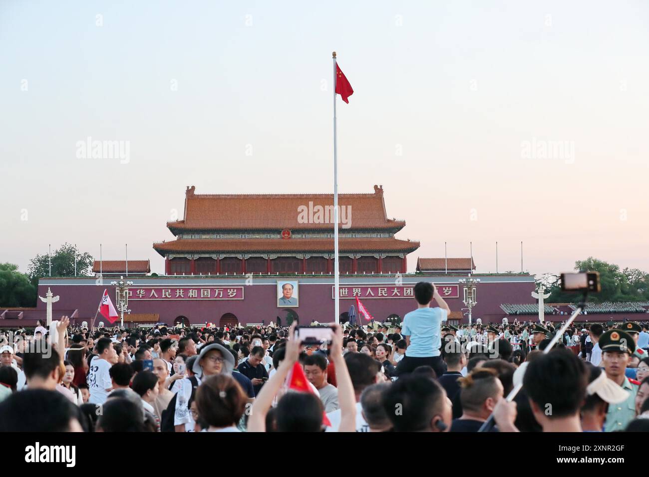 Tourists watch the flag raising ceremony at Tiananmen Square in Beijing ...