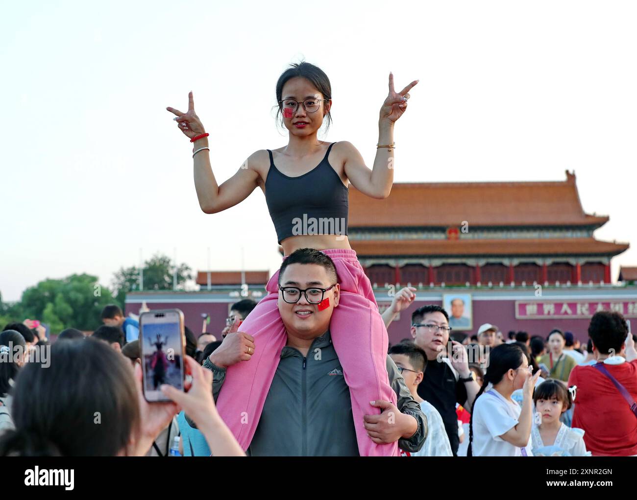 Tourists watch the flag raising ceremony at Tiananmen Square in Beijing ...