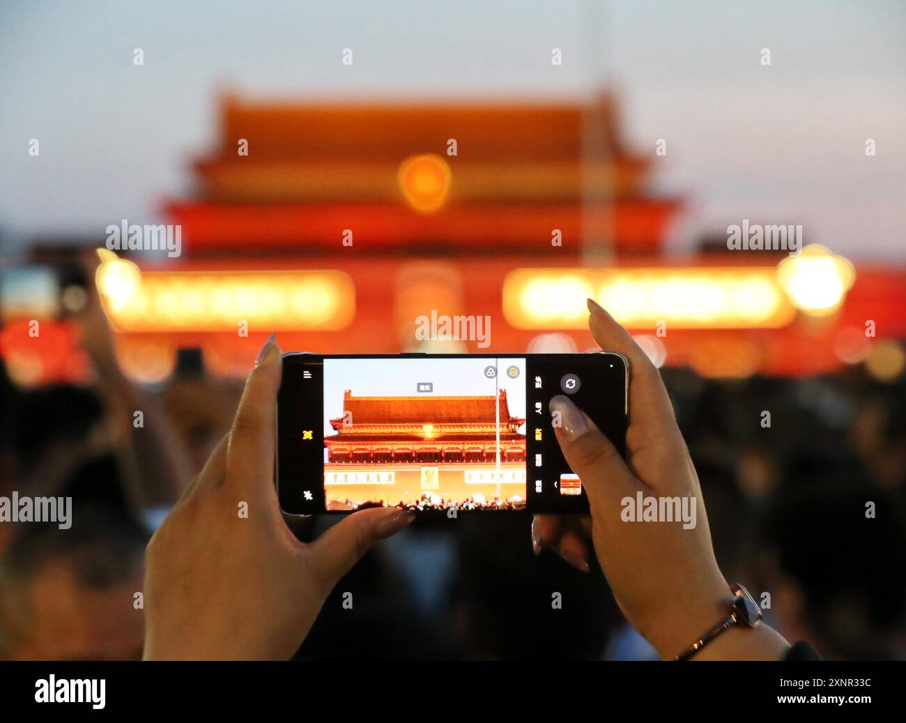 Tourists watch the flag raising ceremony at Tiananmen Square in Beijing ...
