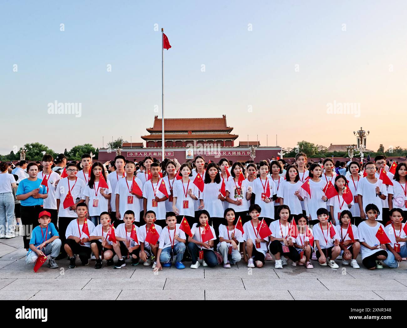 Tourists watch the flag raising ceremony at Tiananmen Square in Beijing ...