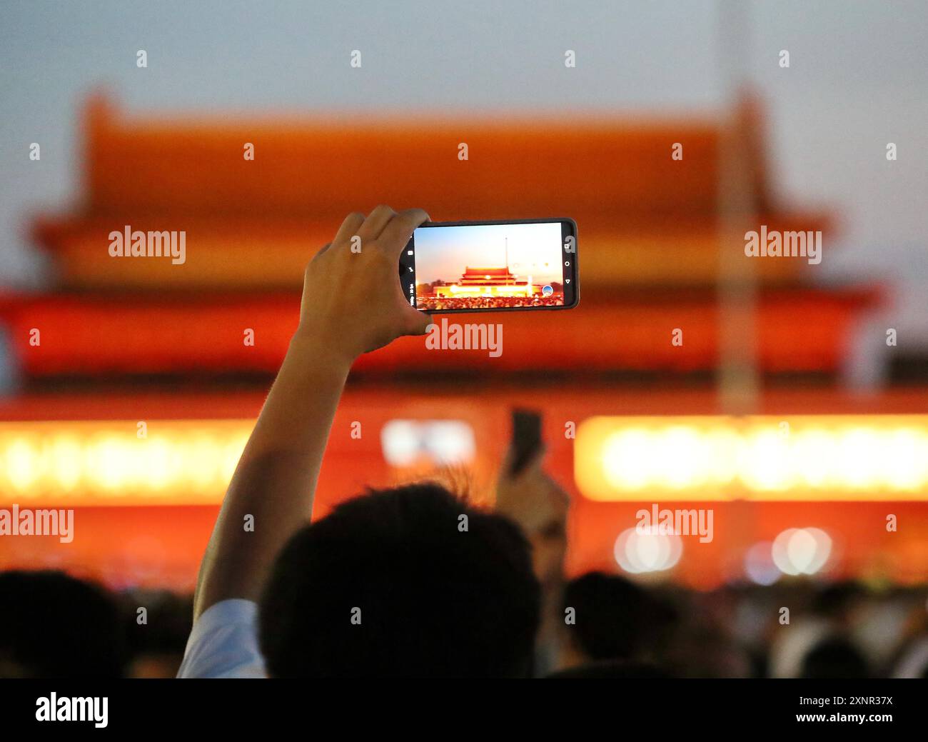 Tourists watch the flag raising ceremony at Tiananmen Square in Beijing ...
