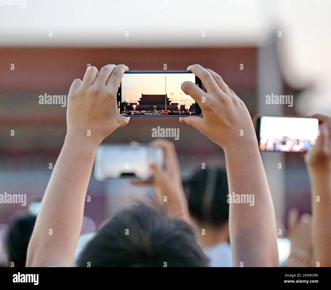 Tourists watch the flag raising ceremony at Tiananmen Square in Beijing ...