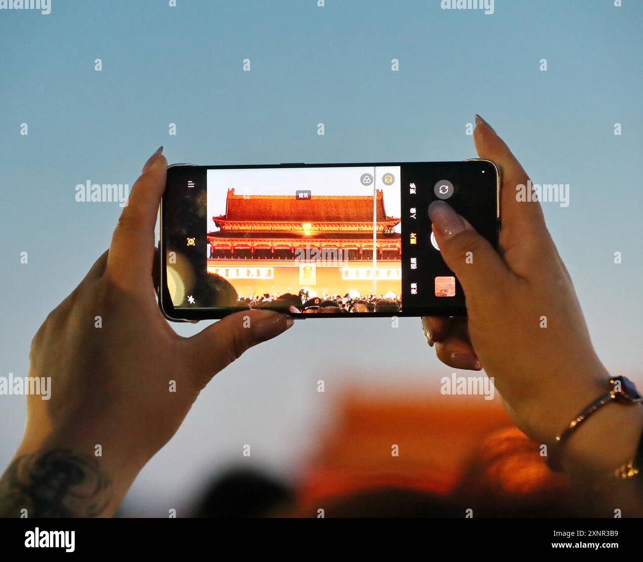 Tourists watch the flag raising ceremony at Tiananmen Square in Beijing ...