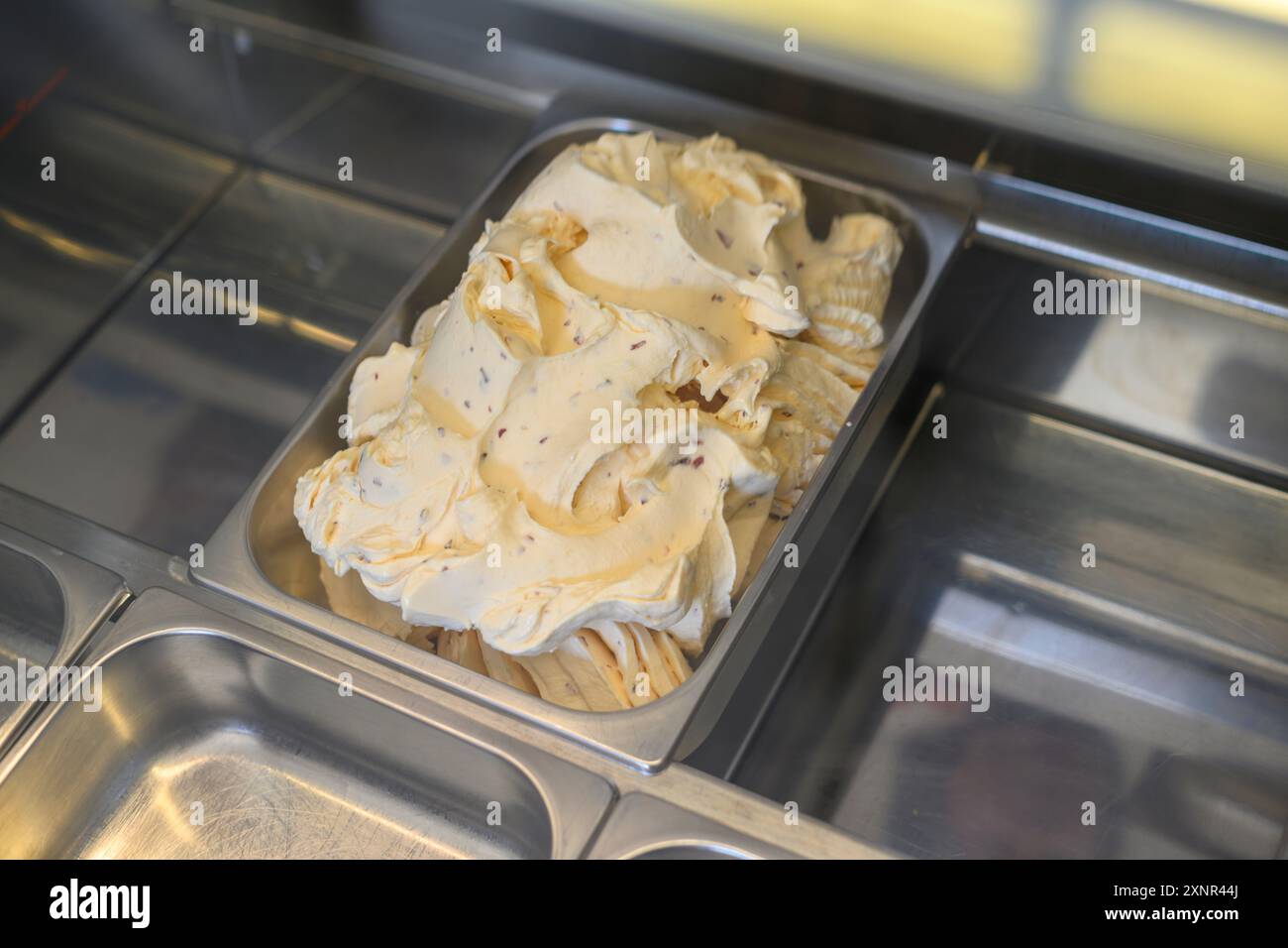 A close-up view of a tub of creamy gelato with swirls and chunks ...