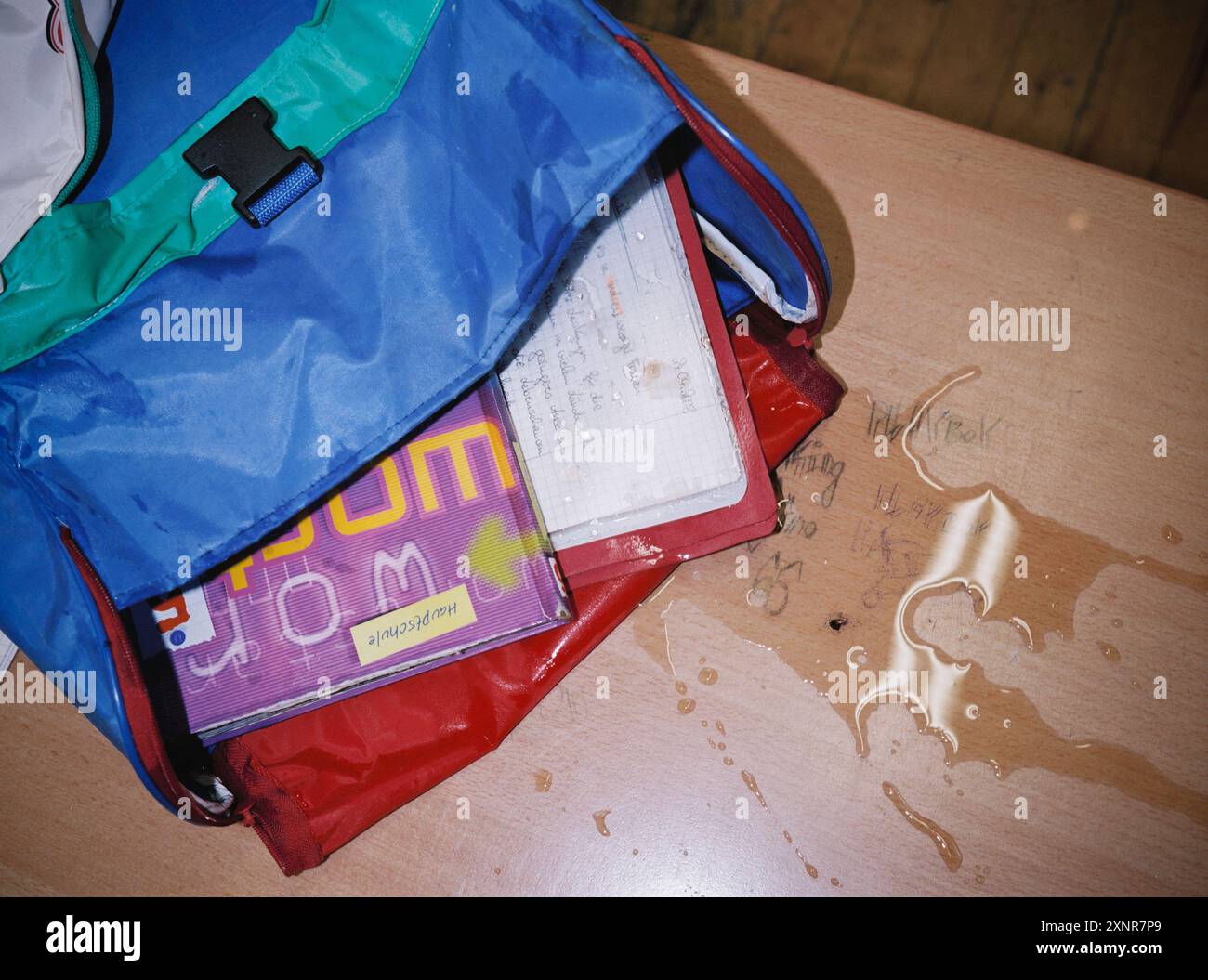 A classroom scene shows a spilled backpack with books and paper on the ...