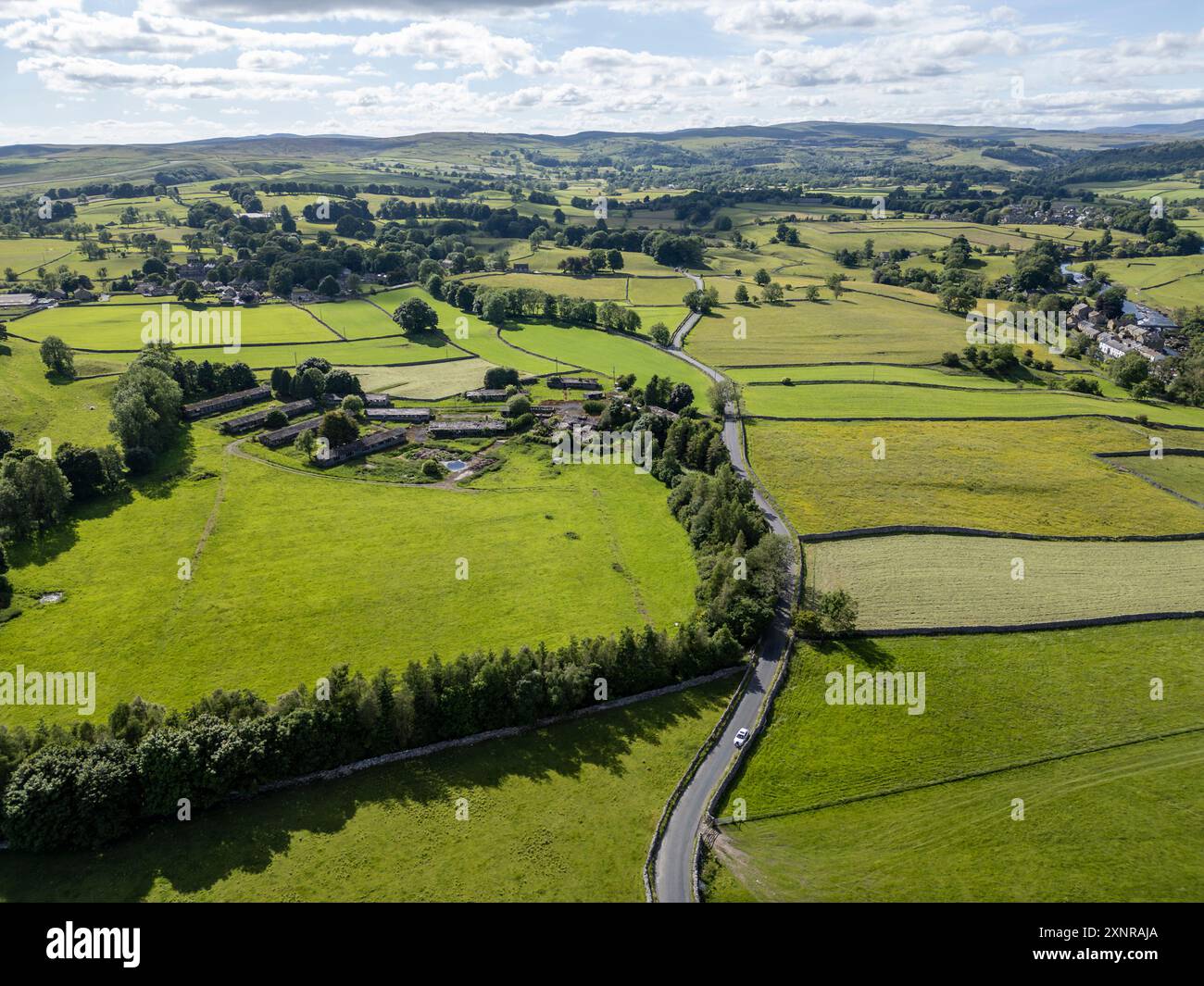 Road passes through farmland and fields in Wharfedale, Yorkshire Dales ...