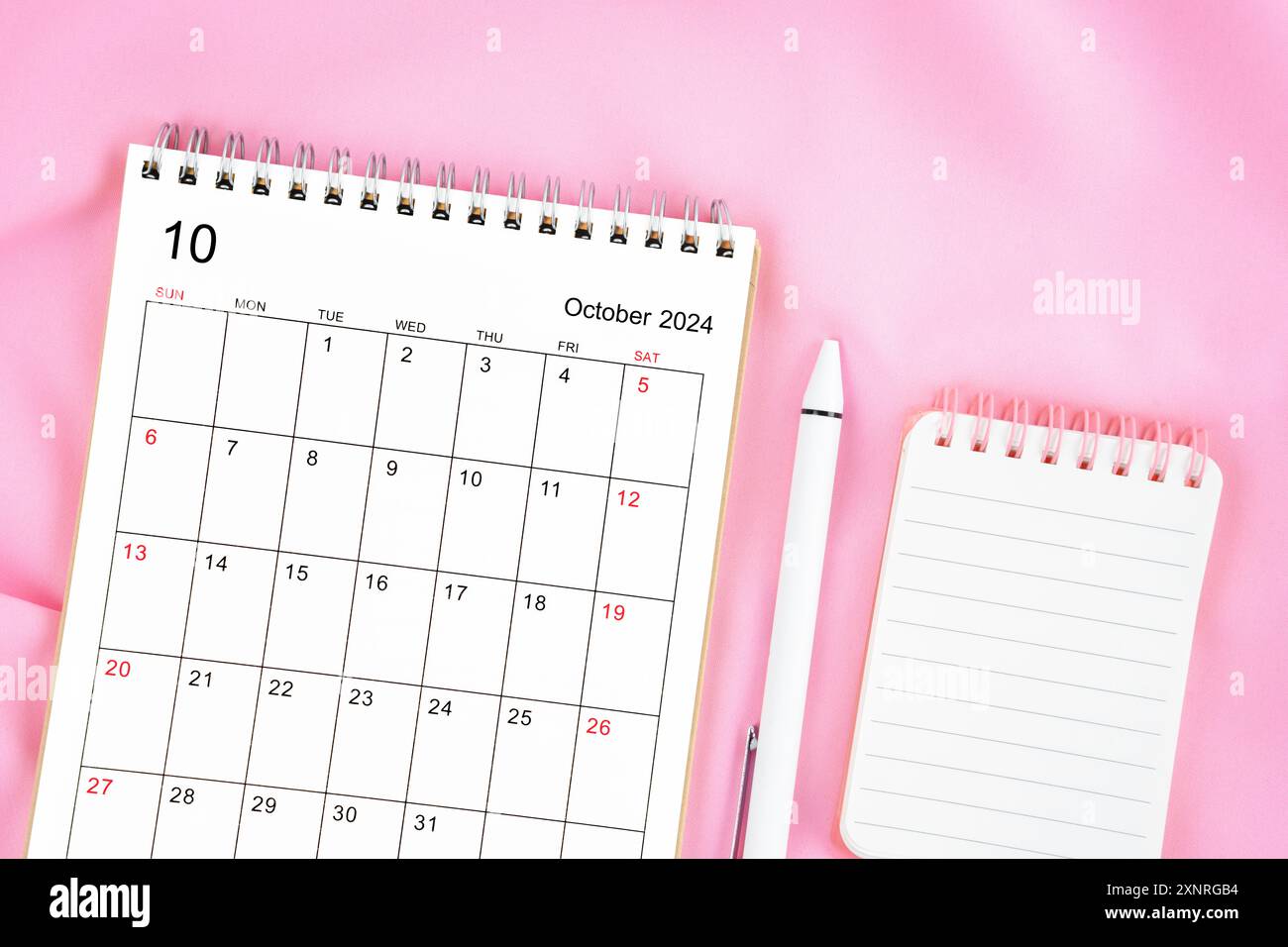 October 2024 month calendar and pen with open diary on pink fabric ...