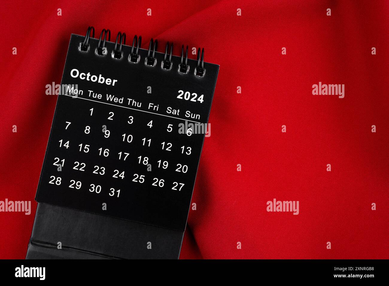 October 2024 Black spiral desktop calendar on red color textile Stock ...