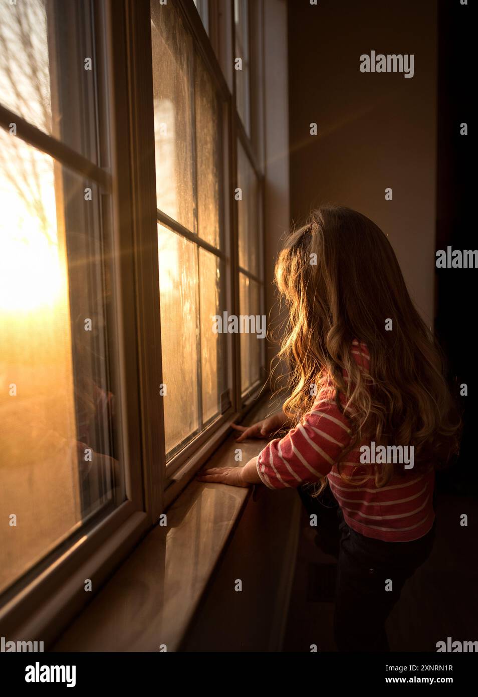 Side view young girl standing in bright sunny window Stock Photo - Alamy