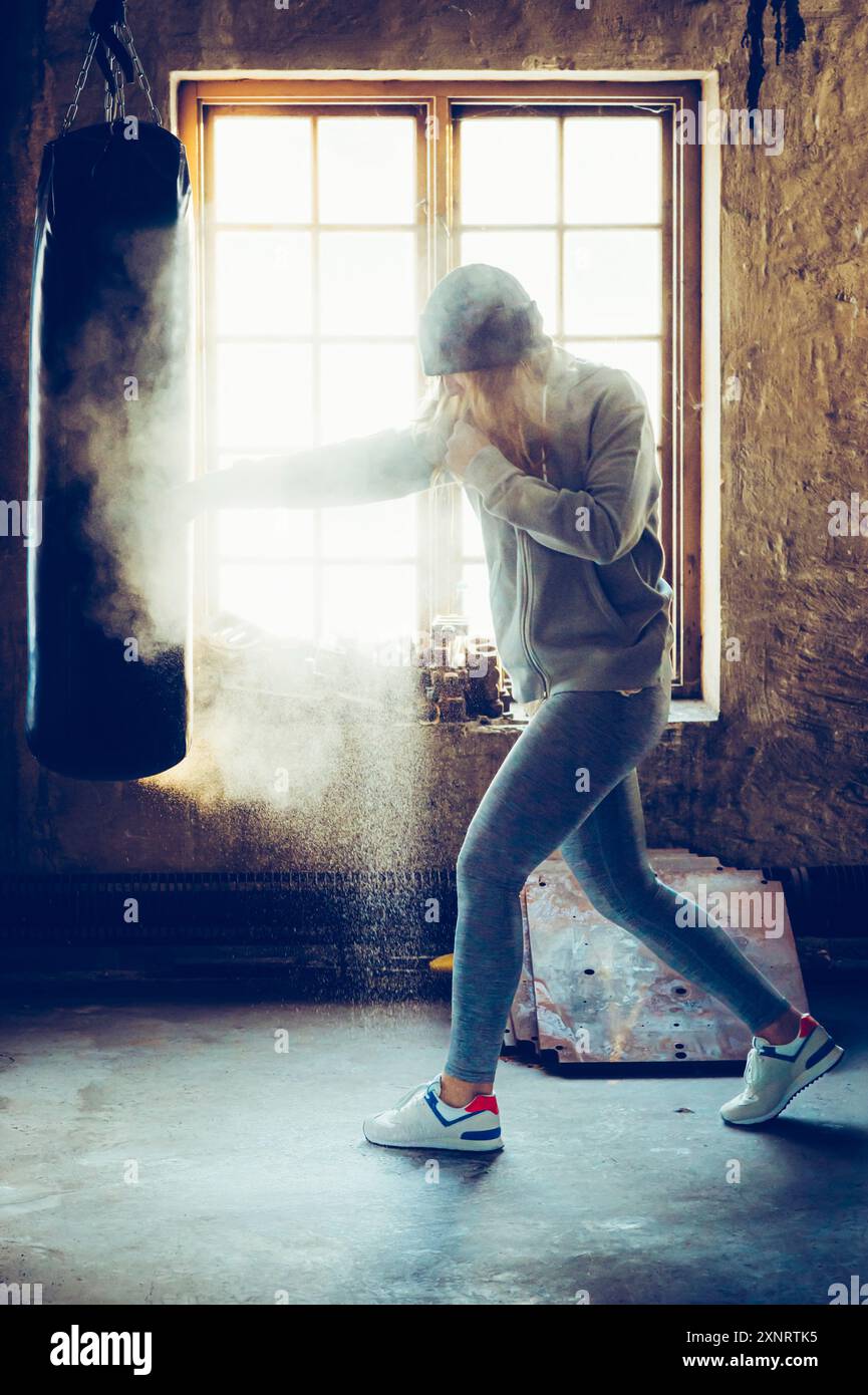 Basic Workout - Woman hitting dusty heavy bag in industrial gym Stock ...