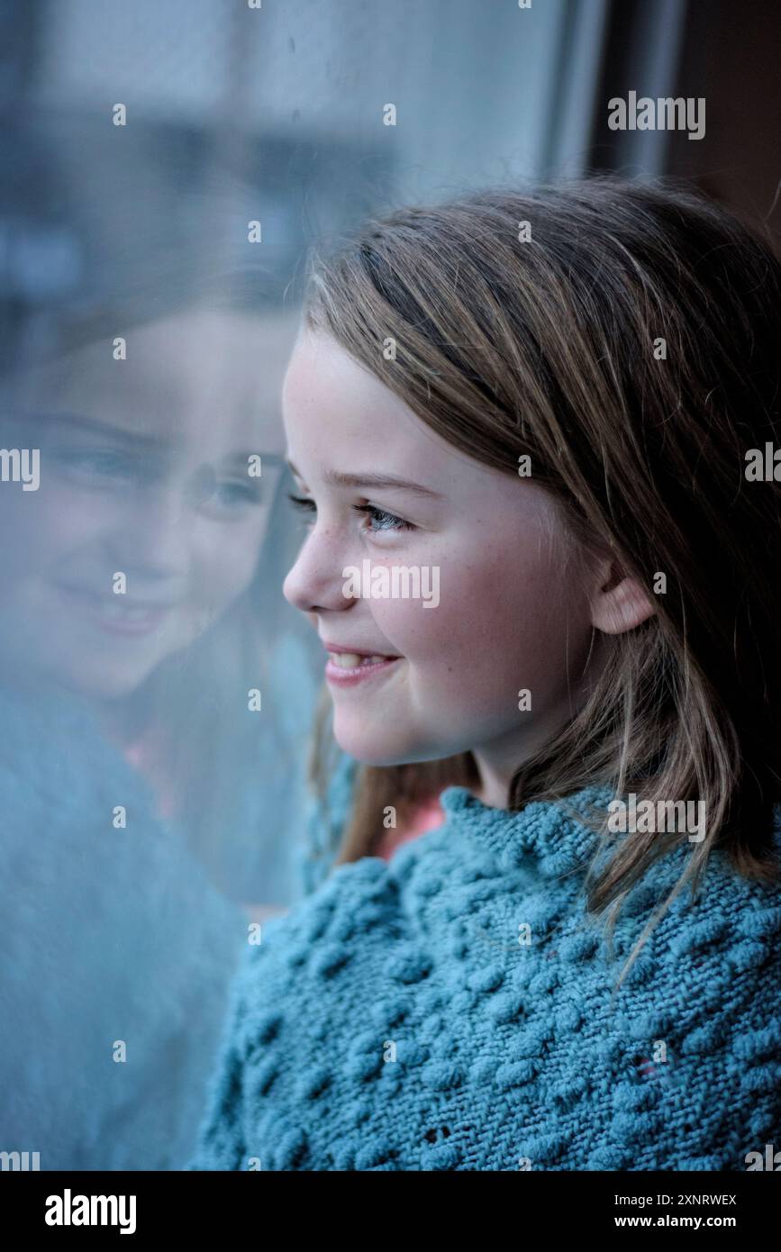 Happy young girl smiling at reflection in window Stock Photo - Alamy