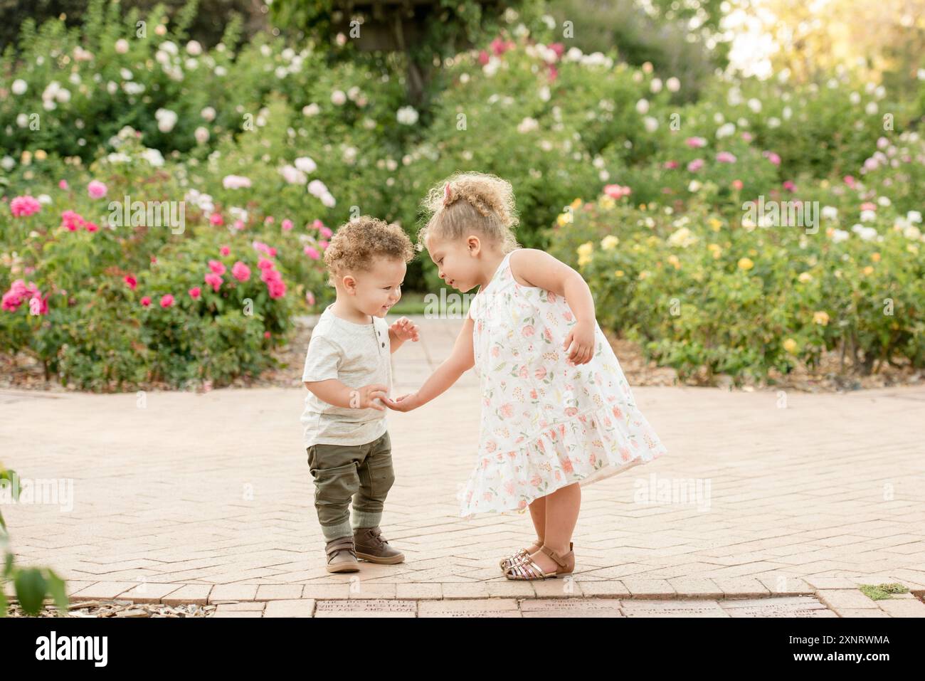 Sister helping brother in the garden Stock Photo - Alamy