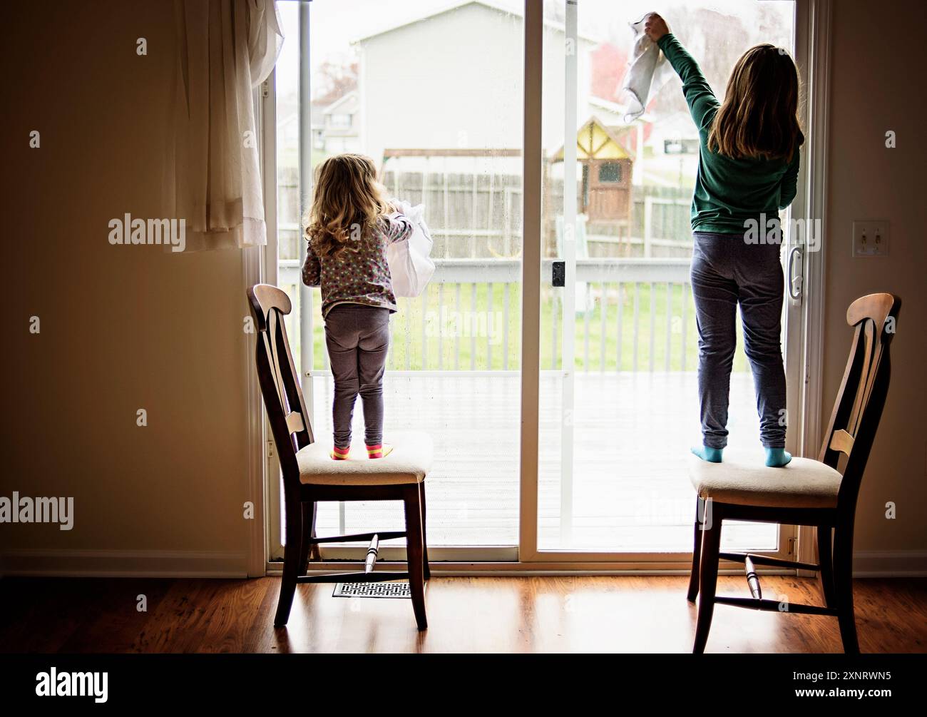 Young sisters washing windows doing chores inside home Stock Photo - Alamy