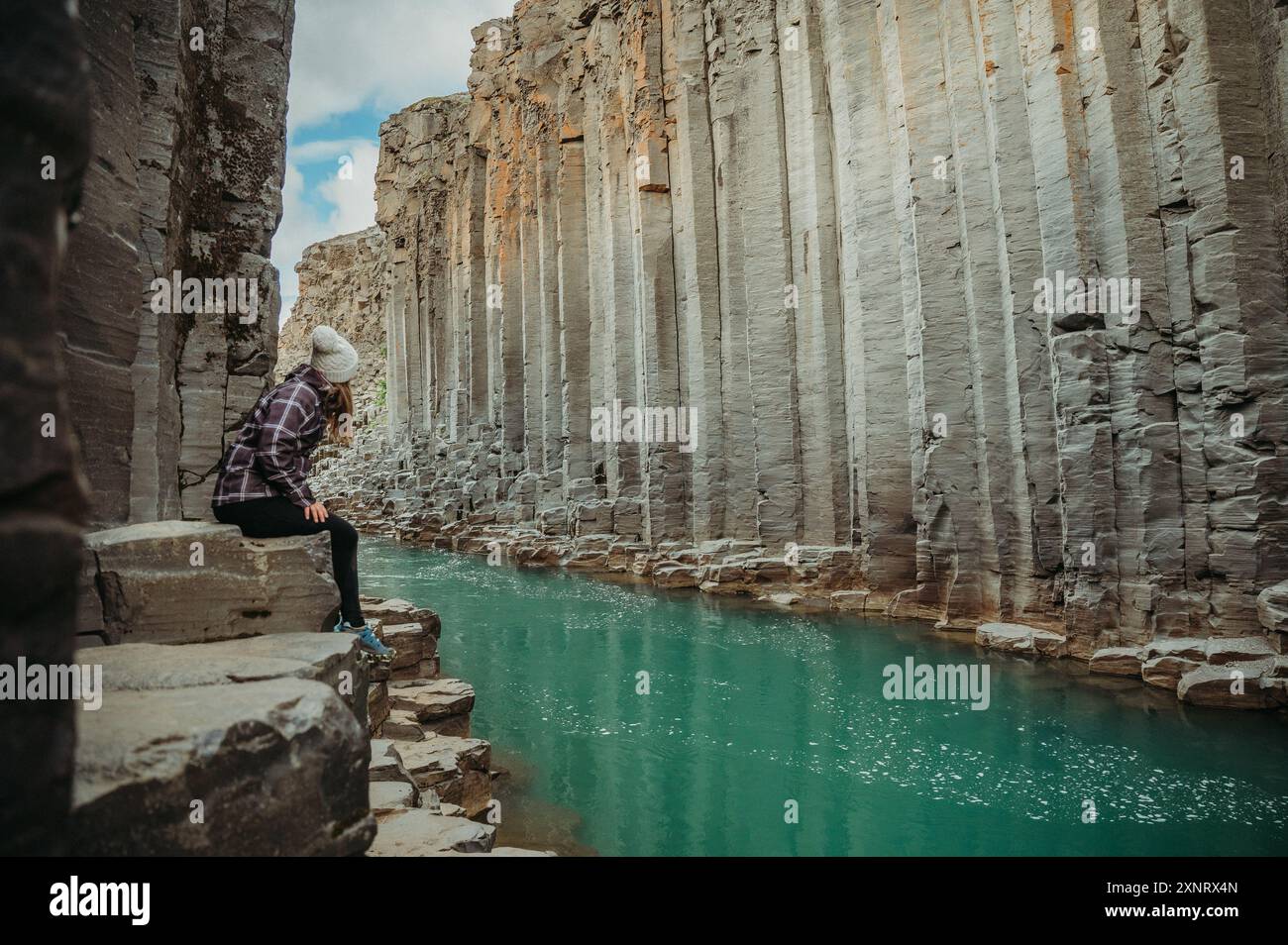 Woman sitting on basalt columns in Stuðlagil Canyon, Iceland Stock ...