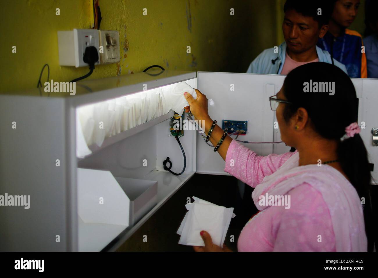 A teacher places sanitary pads in a vending machine installed by the ...