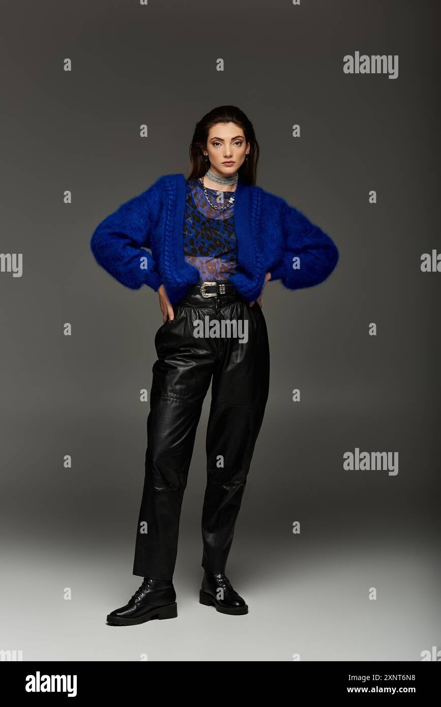 Woman wears blue cardigan, black leather pants, poses confidently ...