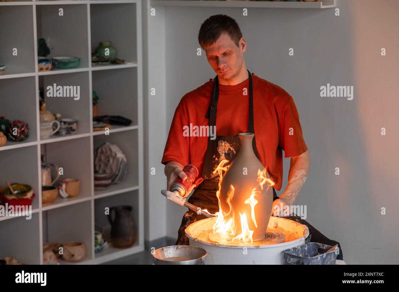A potter burns a jug with a gas burner on a potter's wheel Stock Photo ...