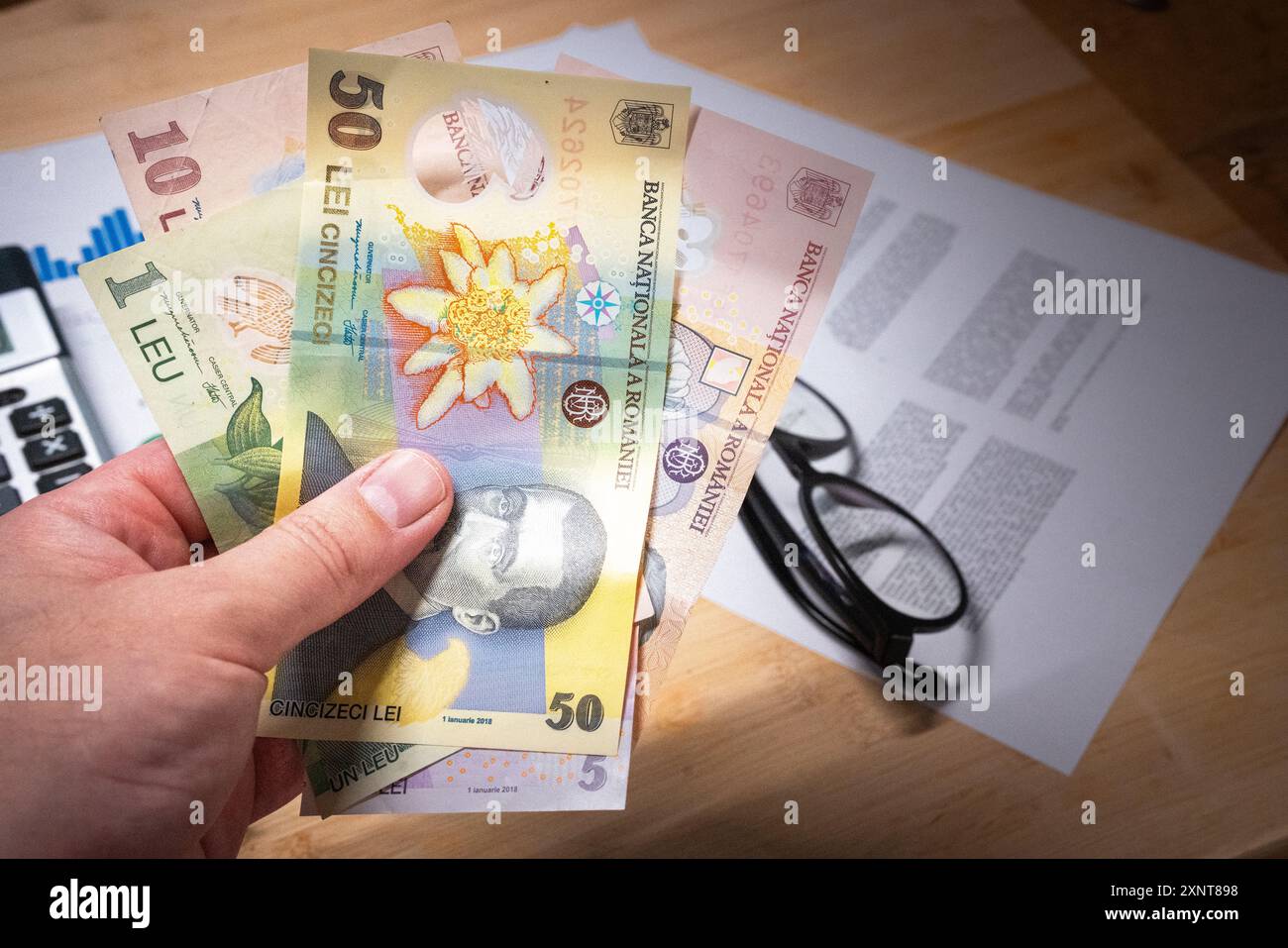 Hand handing over bundle of banknotes. Agreement documents. Romanian ...