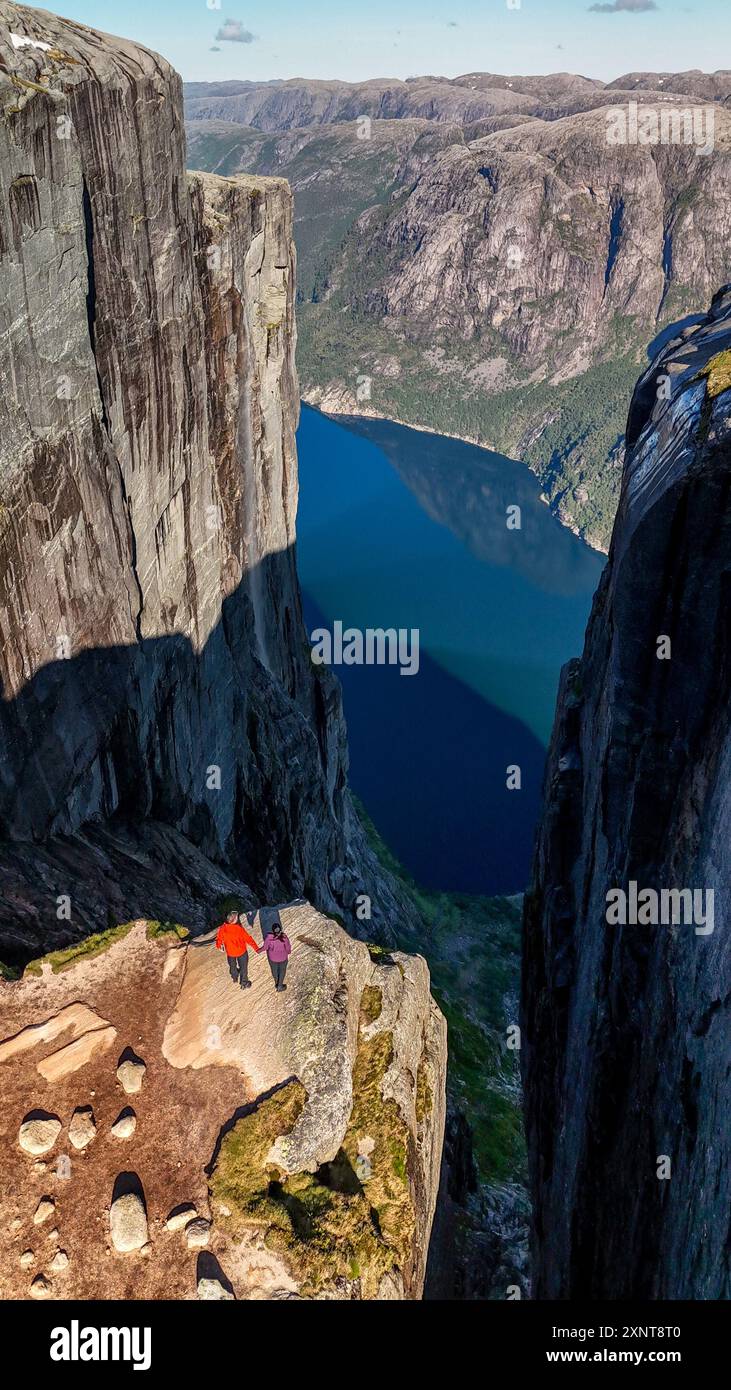 Two hikers stand on the edge of a dramatic cliff hi-res stock ...