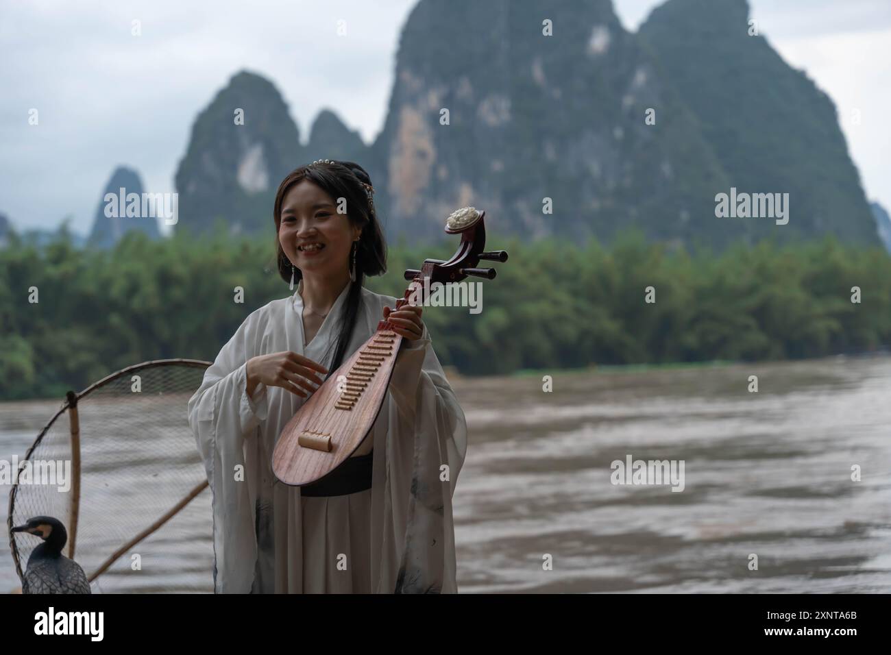 Hanfu girl smiling over Li River puts a pipa traditional instrument in ...