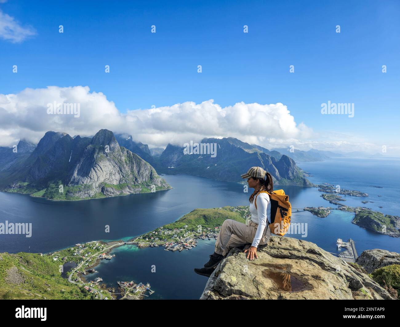 A lone hiker perches on a rocky ledge, gazing across the stunning ...