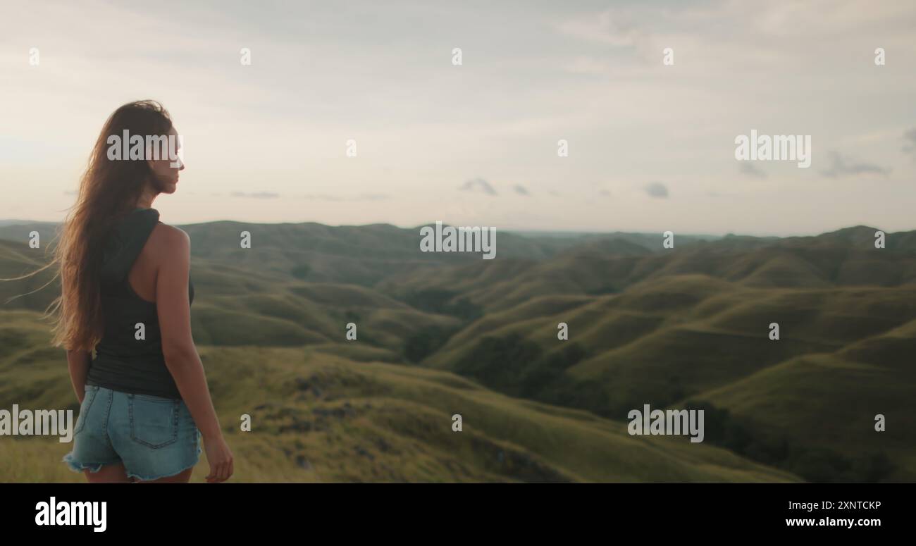 Young woman is embracing the beauty of nature while standing on a ...
