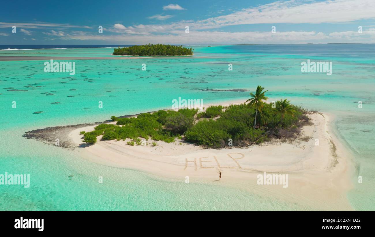 Aerial drone footage of a castaway writing help on the beach of a small ...