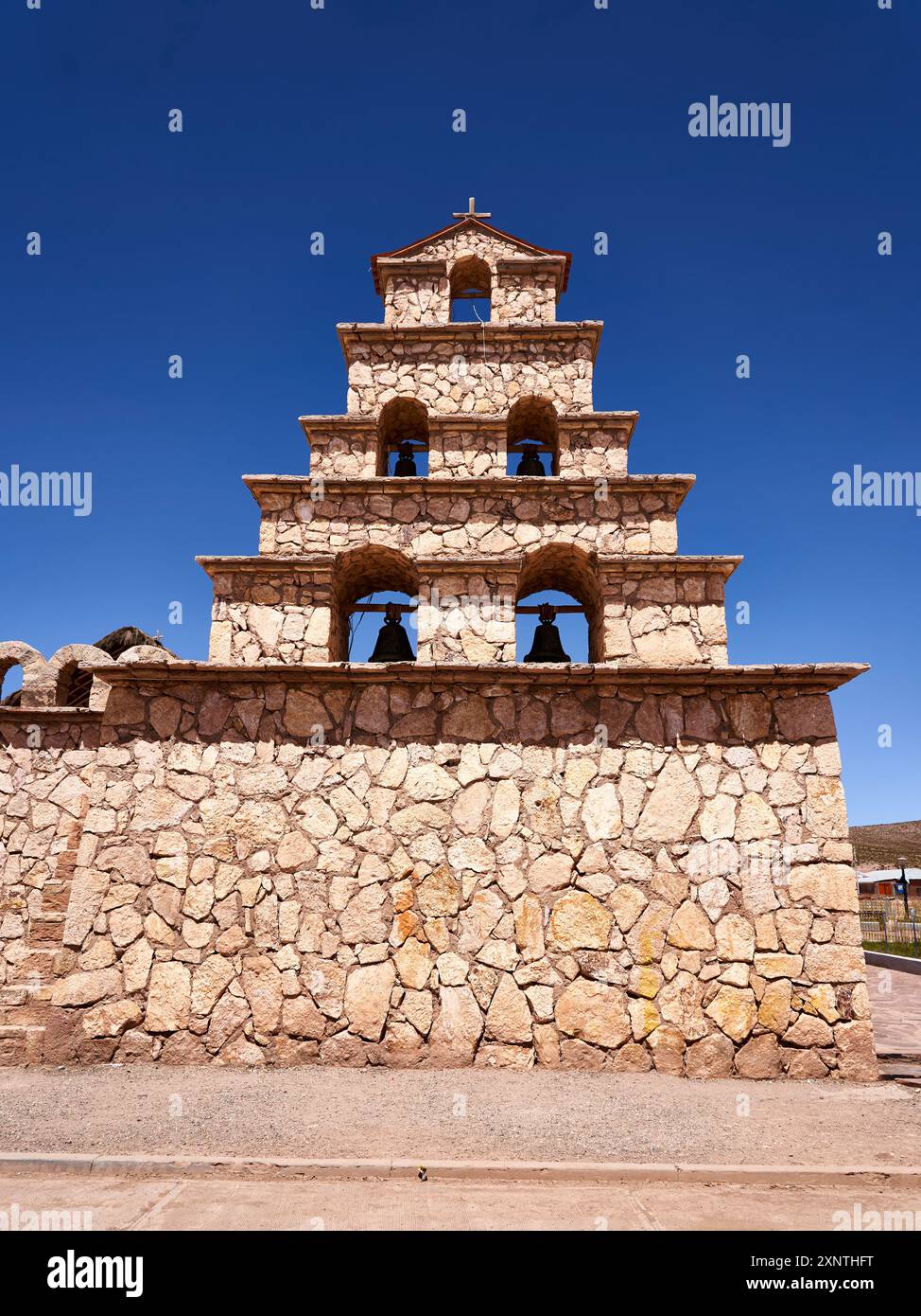 Wide view of a historic stone bell tower with clear blue sky backdrop ...