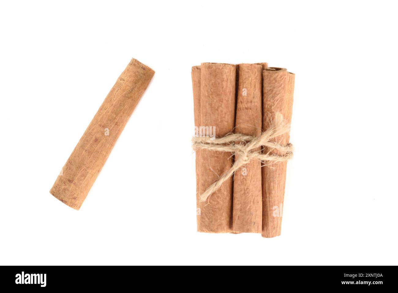 Cassia spice stick lying next to bunch of sticks on white background ...