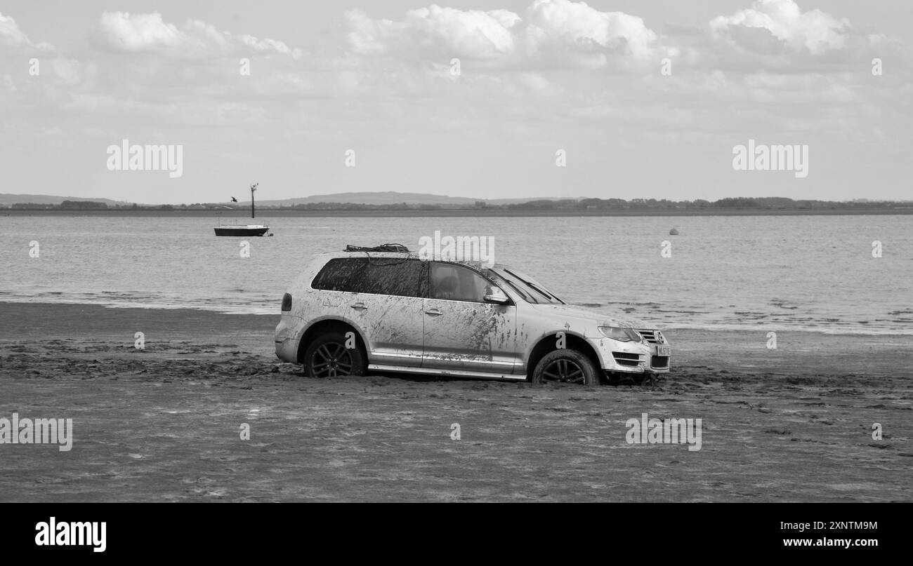 A motor car stuck fast in the mud, as the tide comes in Stock Photo - Alamy