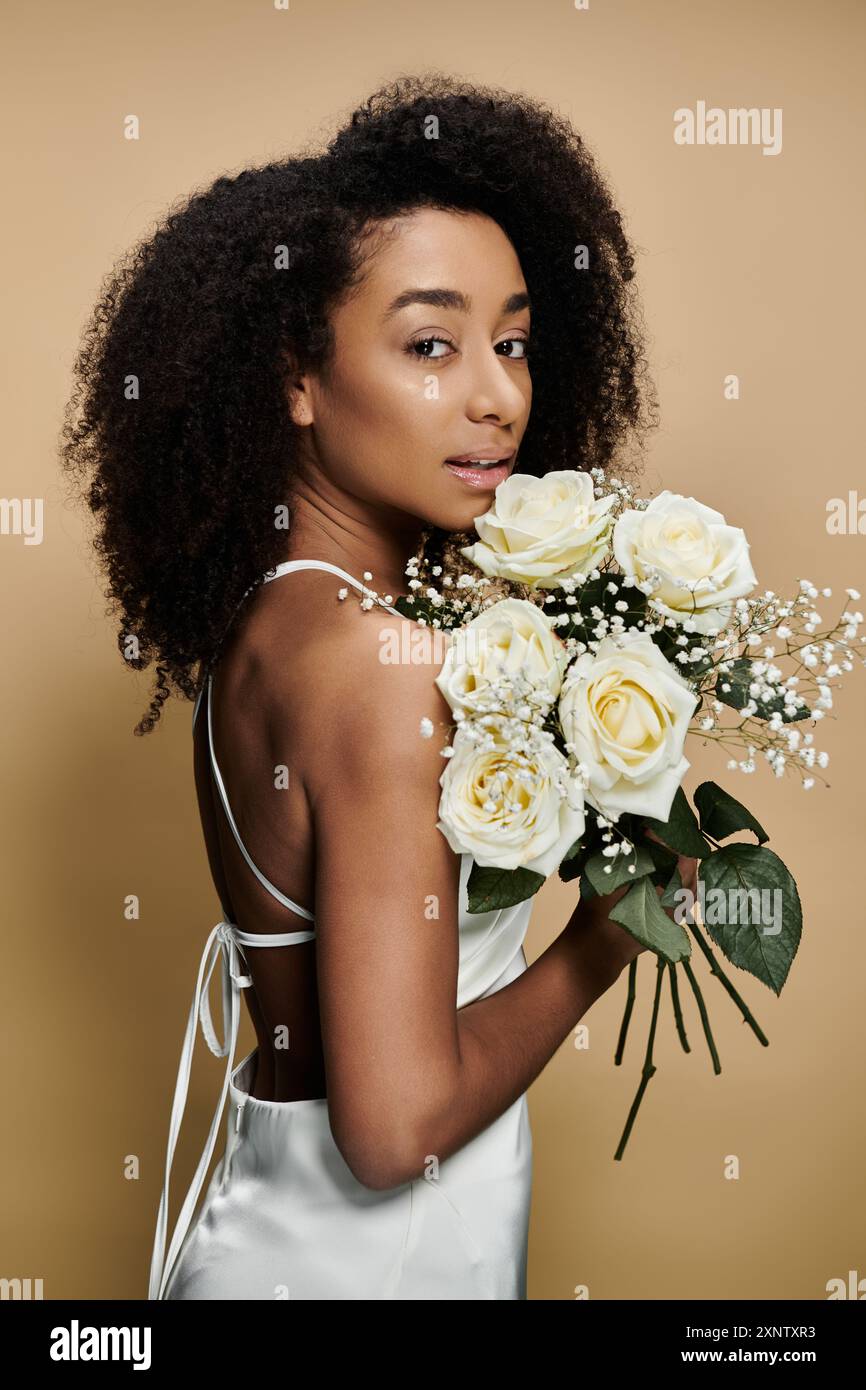 An African American woman in a white dress holds a bouquet of white ...