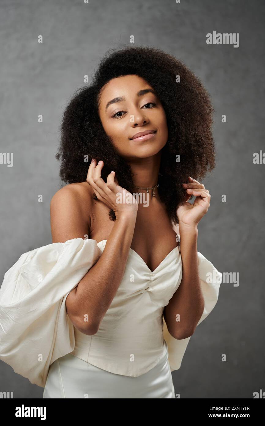 An African American bride in a white wedding dress poses against a gray ...