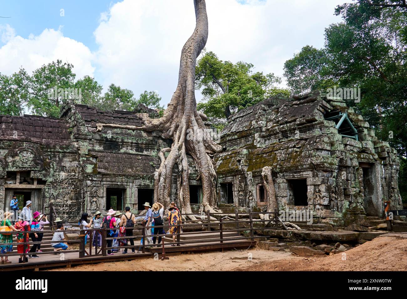 A group of tourists exploring the ancient Angkor Thom temple in ...