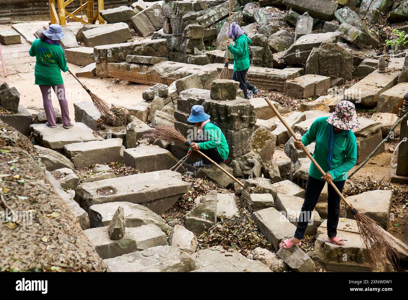 Group of workers in green uniforms cleaning the ancient stone ruins of ...