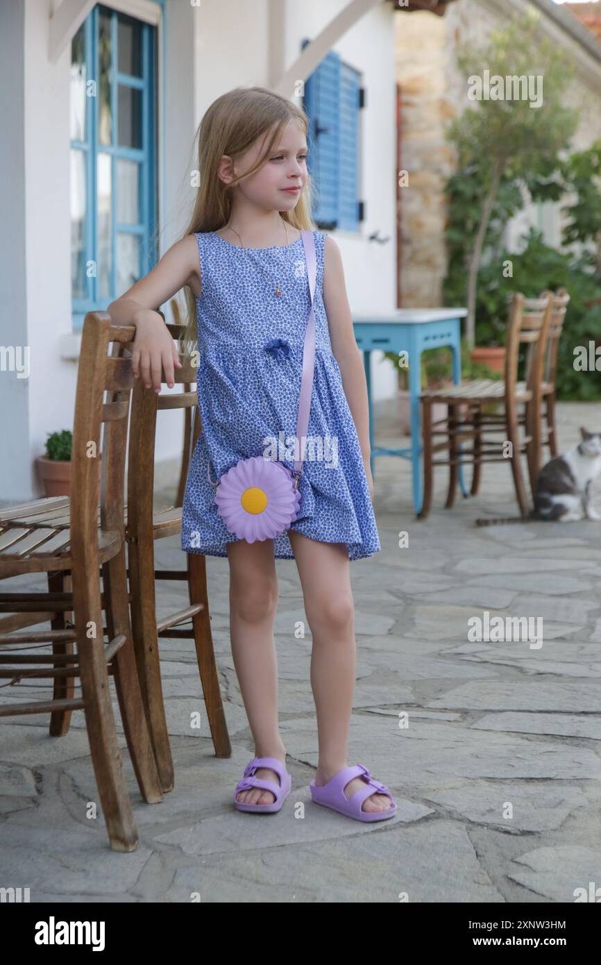 Cute little tourist girl in blue summer dress in Greece village on the ...