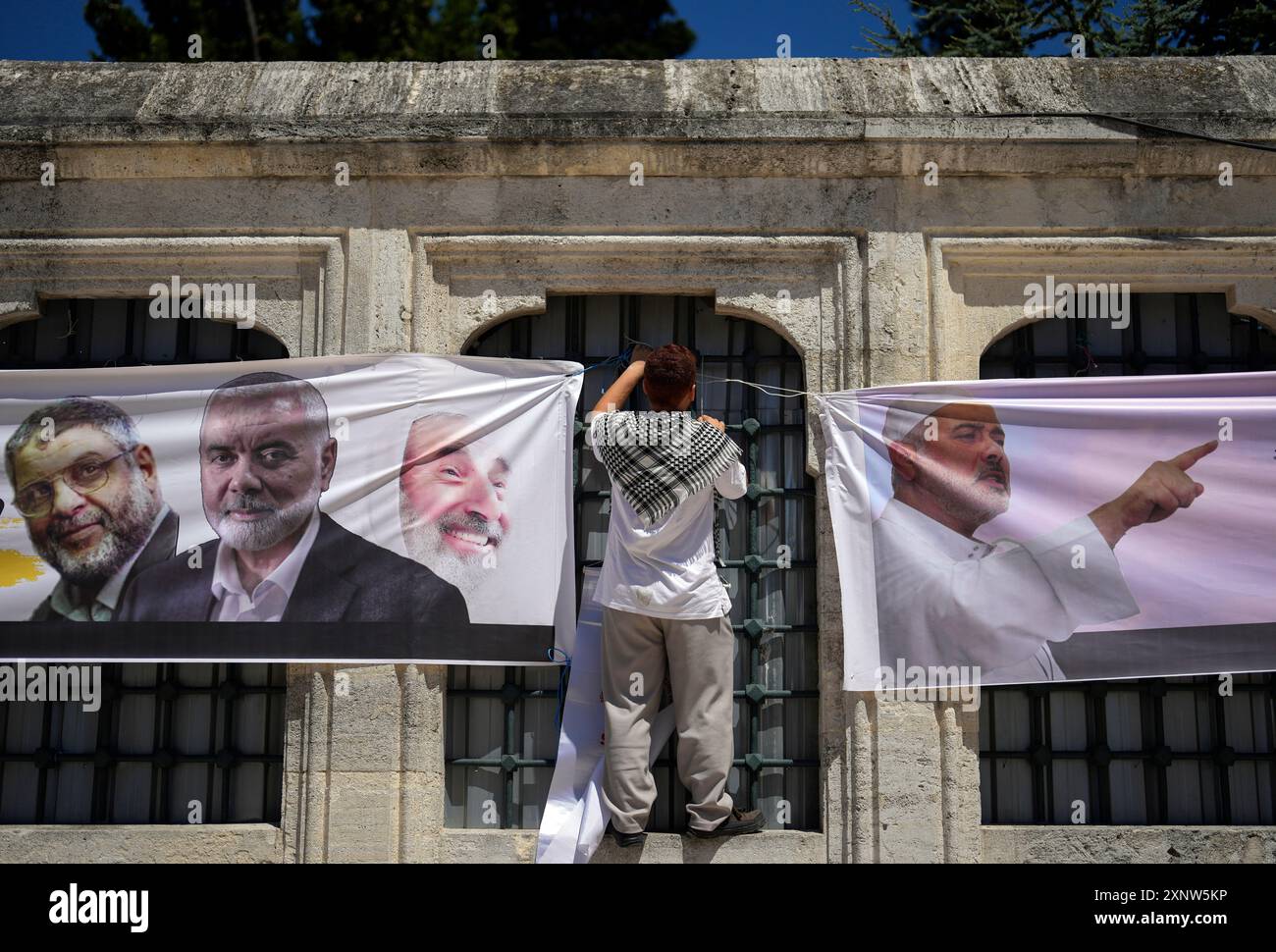 A man hangs banners with pictures of killed Hamas leader Ismail Haniyeh ...