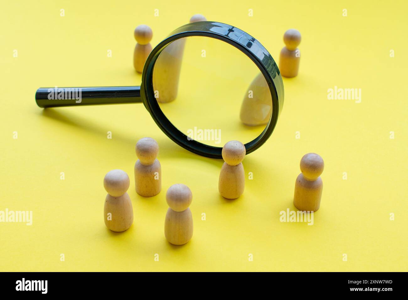 Magnifying glass surrounded by wooden figures. This can represent ...