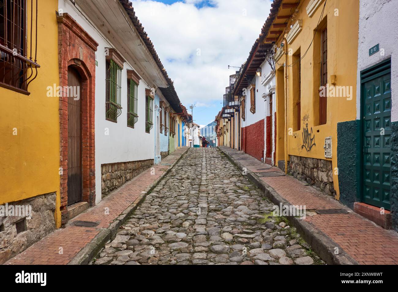 Scenic cobblestone street lined with vibrant, colorful colonial houses ...