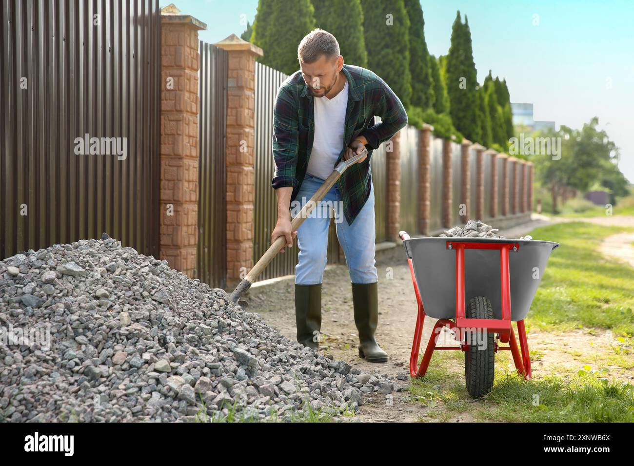Man picking stones up with shovel and wheelbarrow outdoors Stock Photo ...