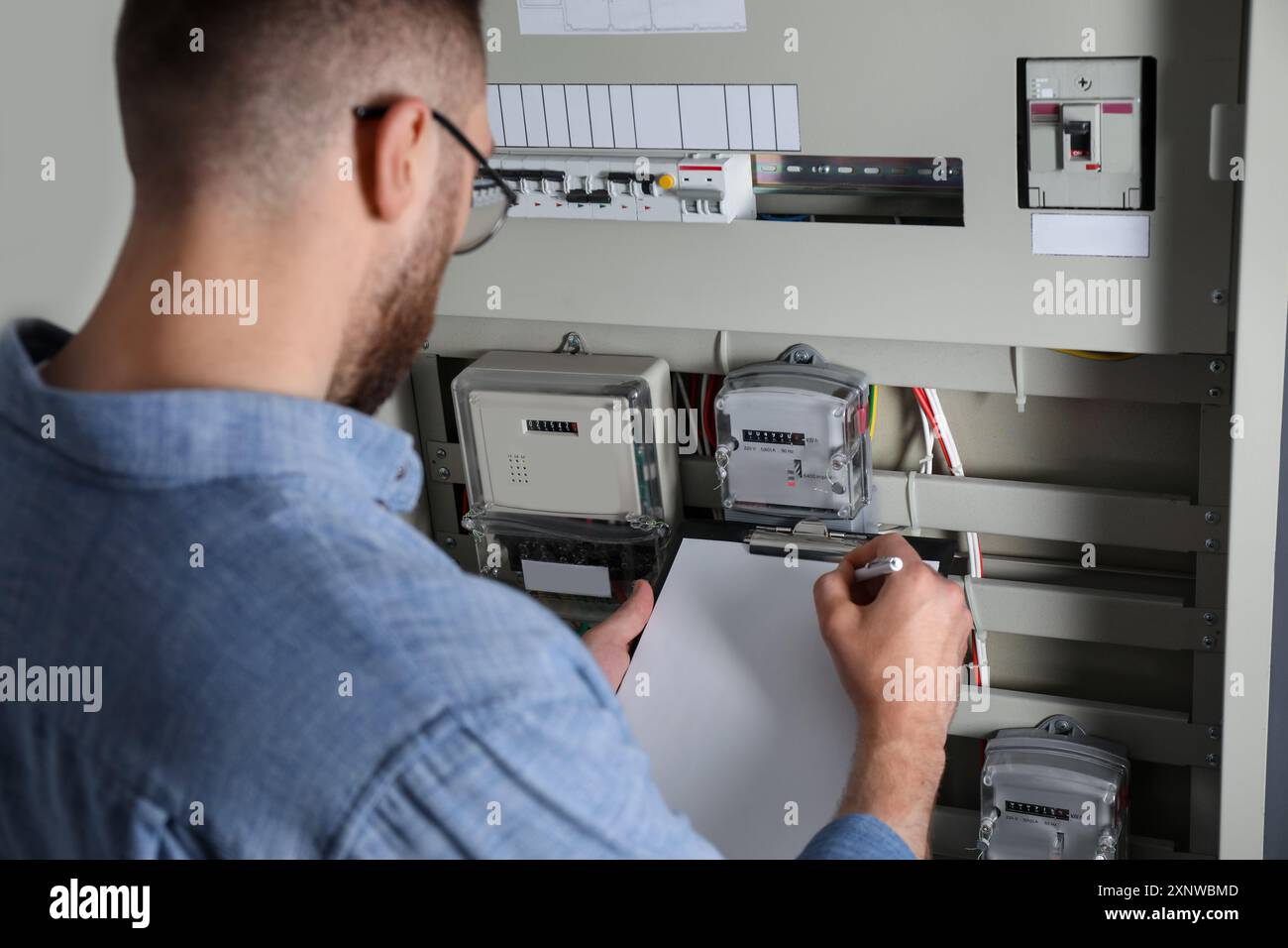 Technician worker with clipboard inspecting electricity meter, closeup ...