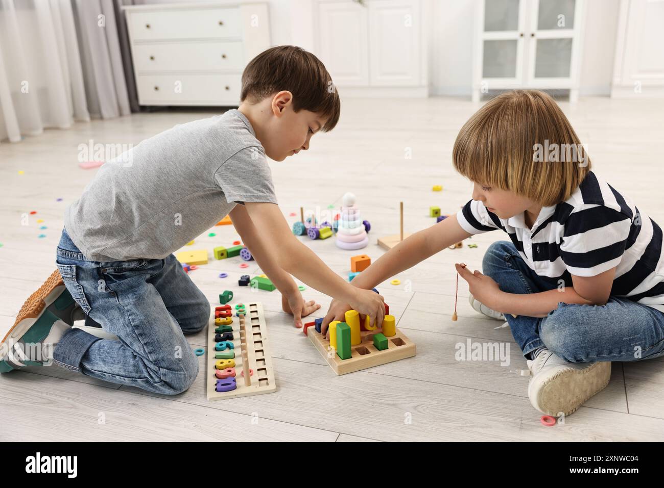 Cute little children playing with wooden blocks on floor indoors Stock ...