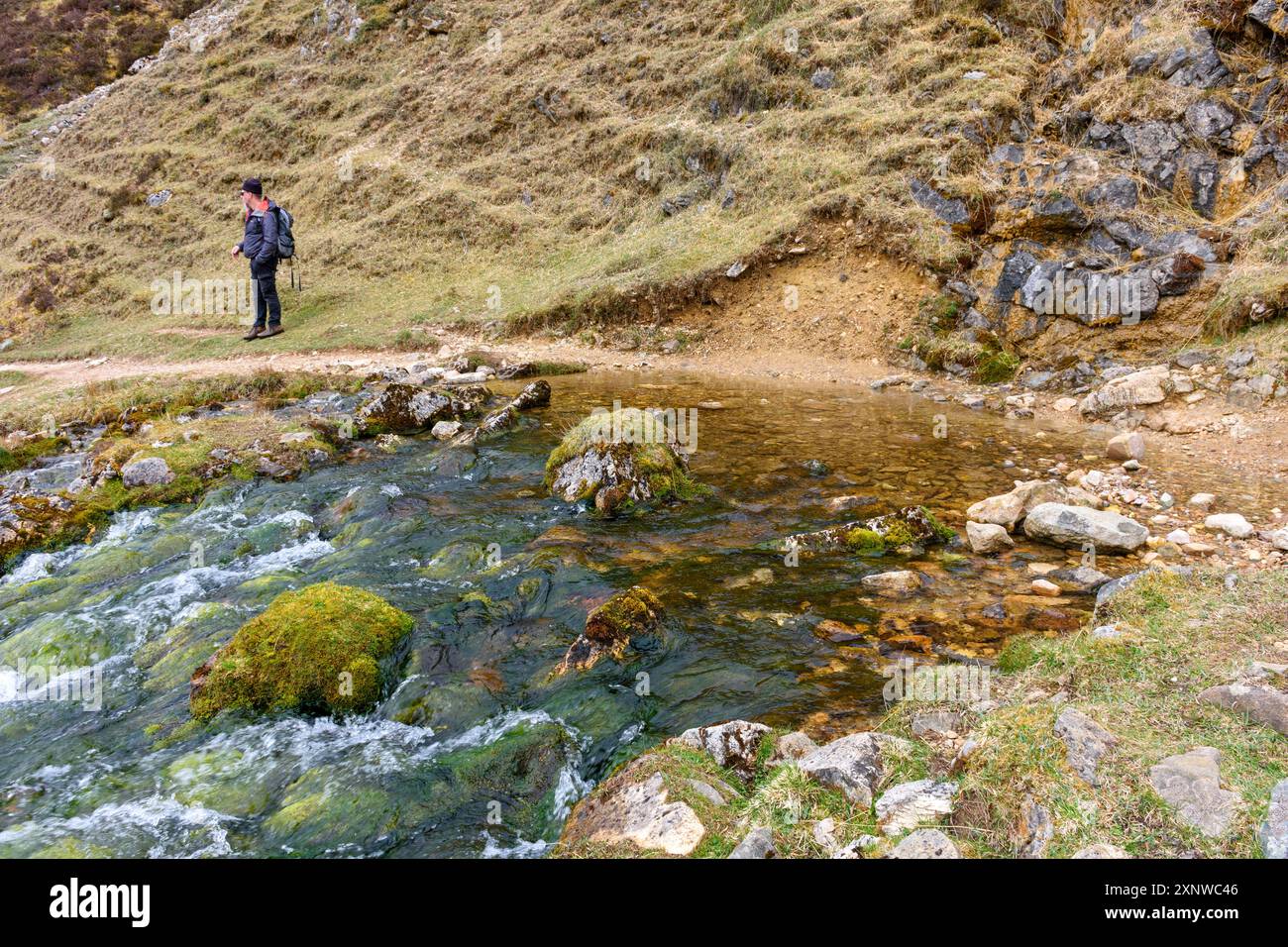 A walker passing a large spring which emerges from the ground, on the ...