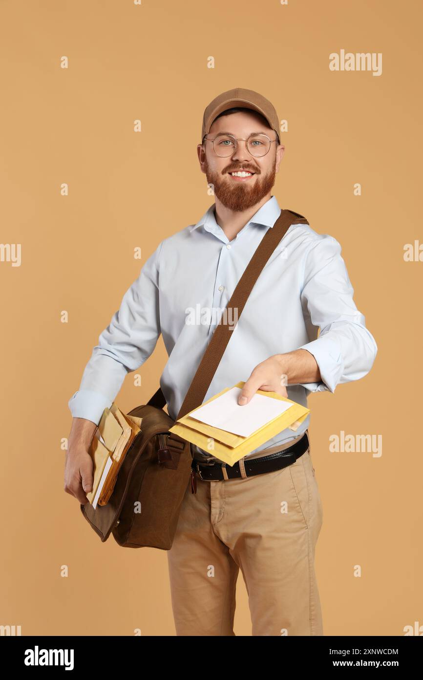 Happy young postman with leather bag delivering letters on brown ...