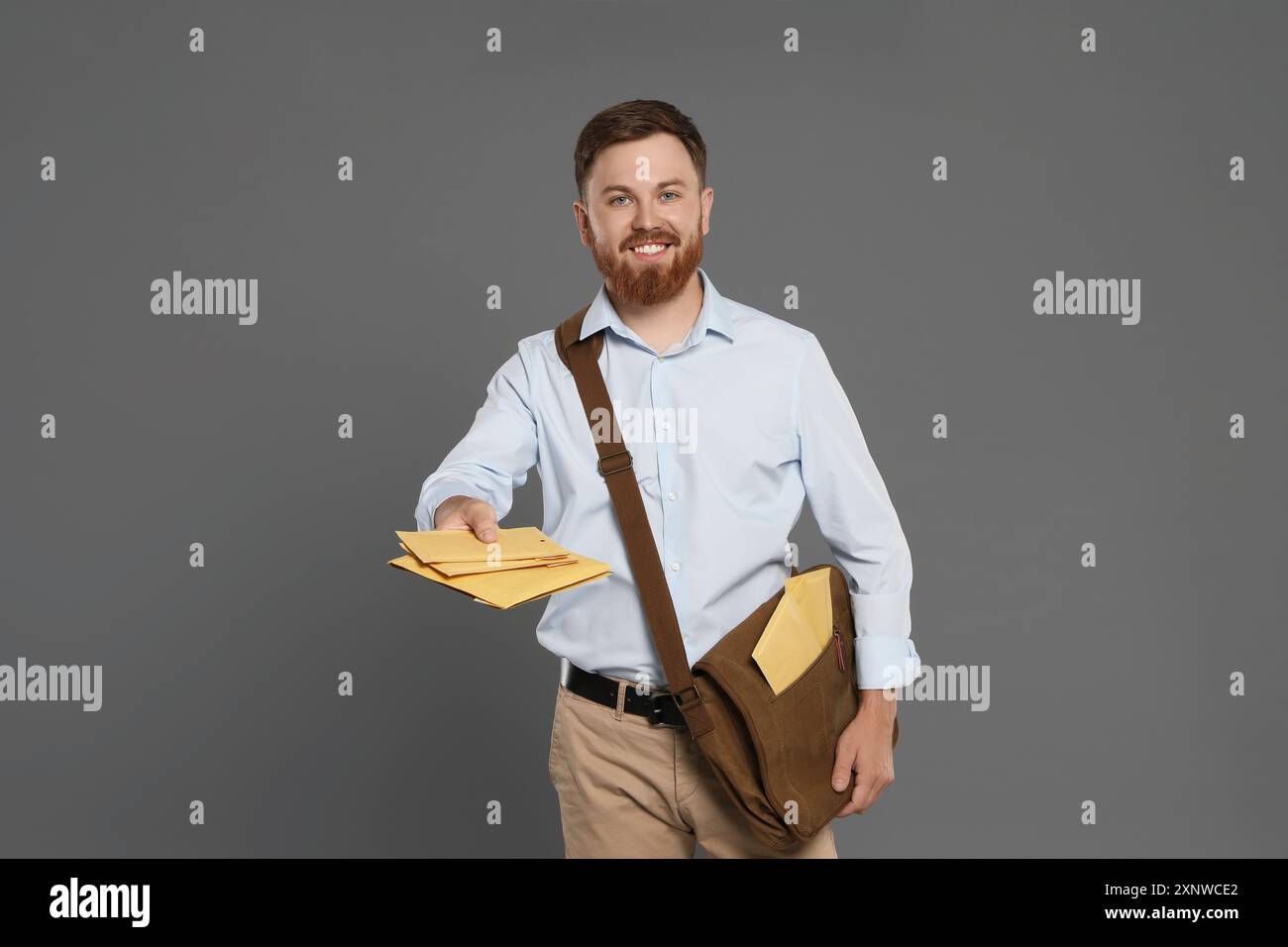 Postman with brown bag delivering letters on grey background Stock ...